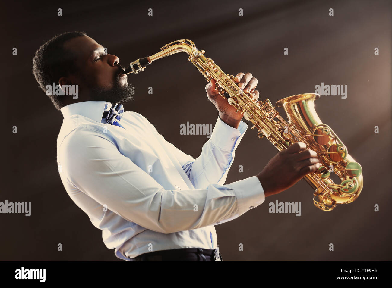 African American jazz musician playing the saxophone on grey background ...