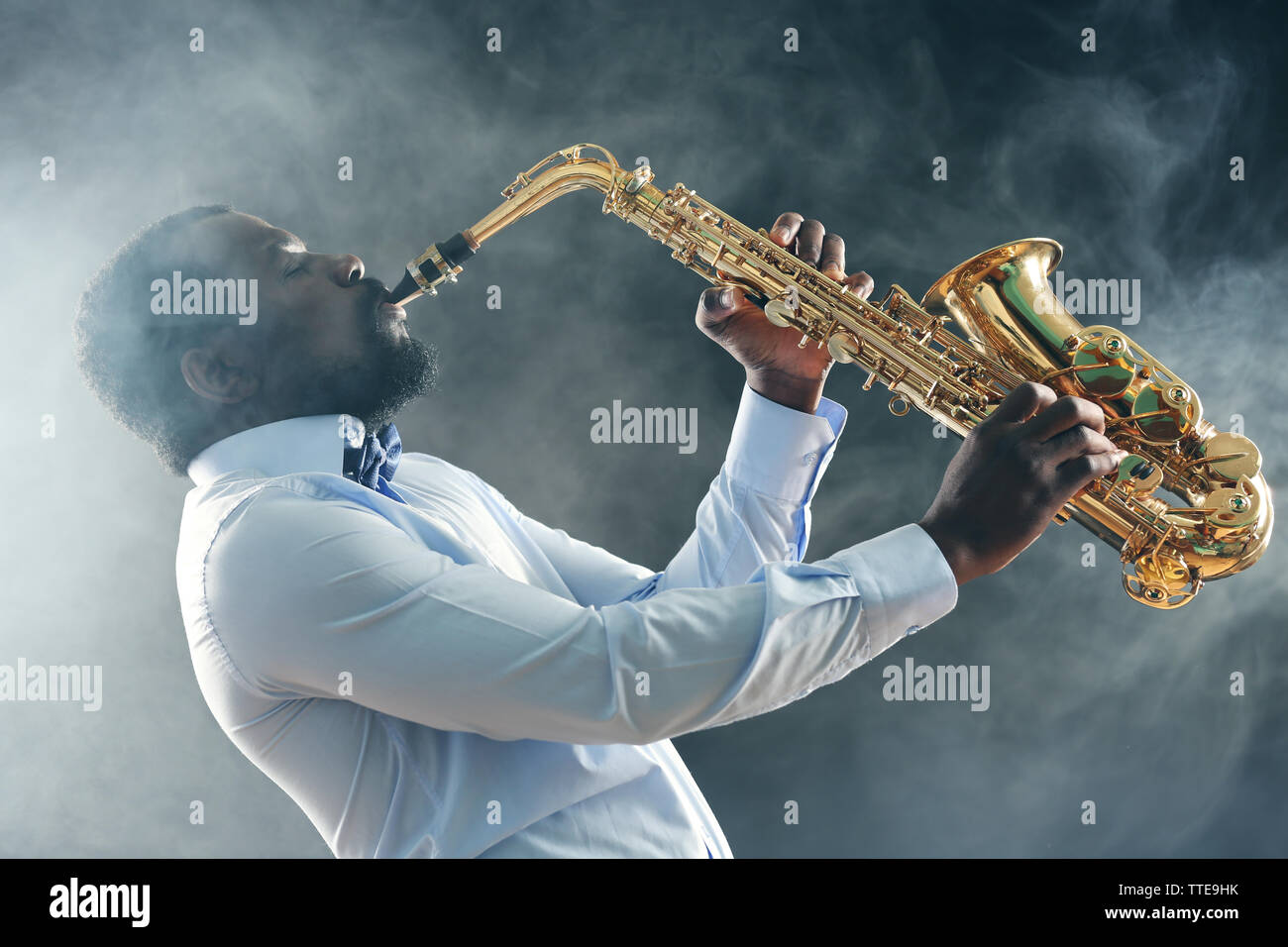 African American jazz musician playing the saxophone against smoky ...