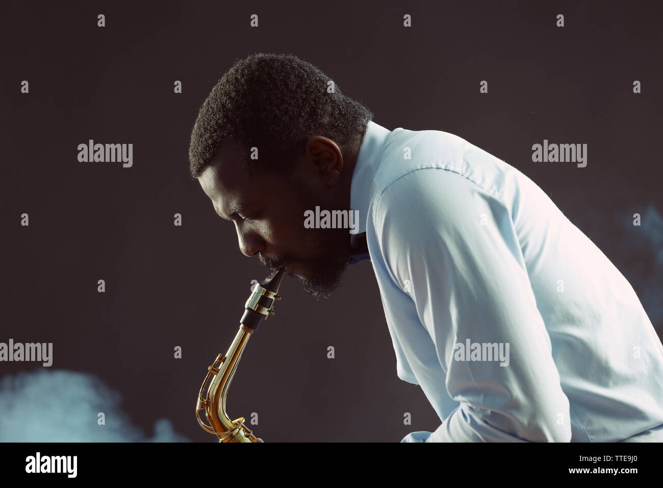 African American jazz musician playing the saxophone on grey background ...