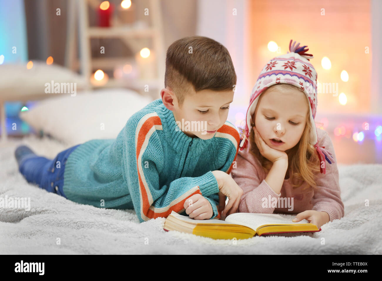 Cute children read book on the floor in the decorated Christmas room ...