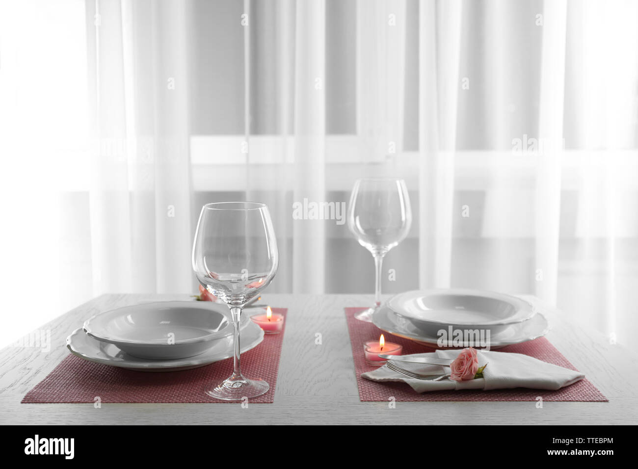 Table setting for two person with dishes and cutlery on pink napkin ...