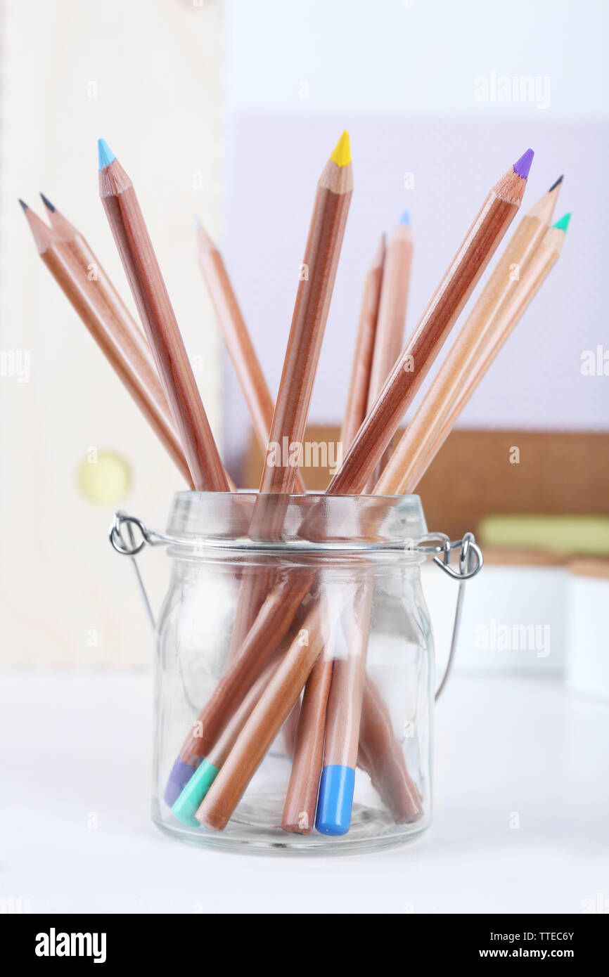 Set of coloured pencils in a glass pot on a table Stock Photo - Alamy