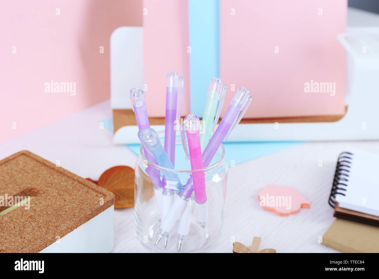 Set of coloured pens in a glass pot on white table Stock Photo - Alamy