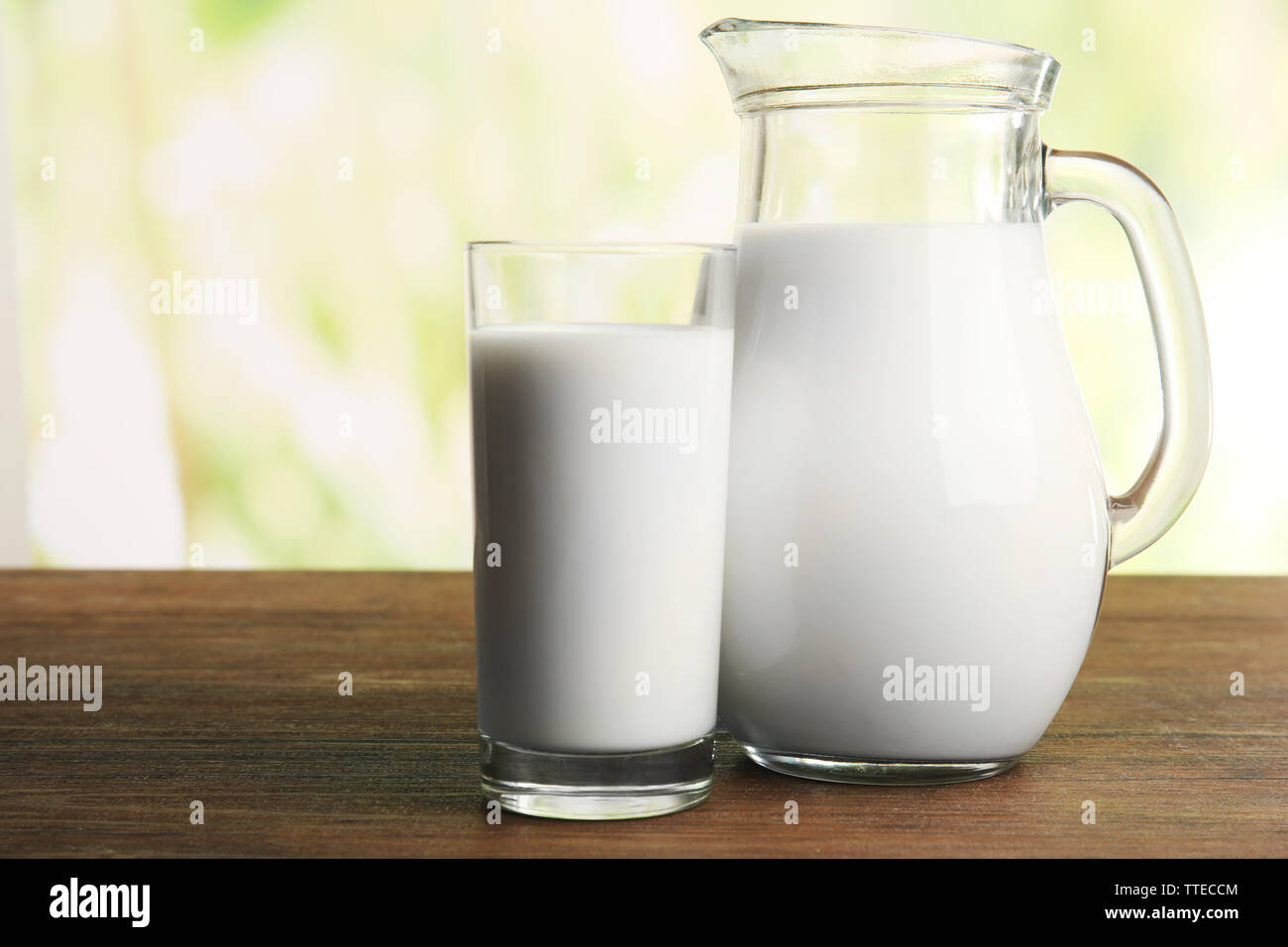 Milk in jar and in glass on table on blurred natural background Stock ...