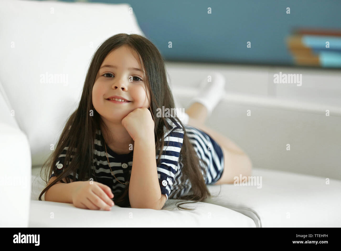 Beautiful little girl lying on sofa in the room Stock Photo - Alamy