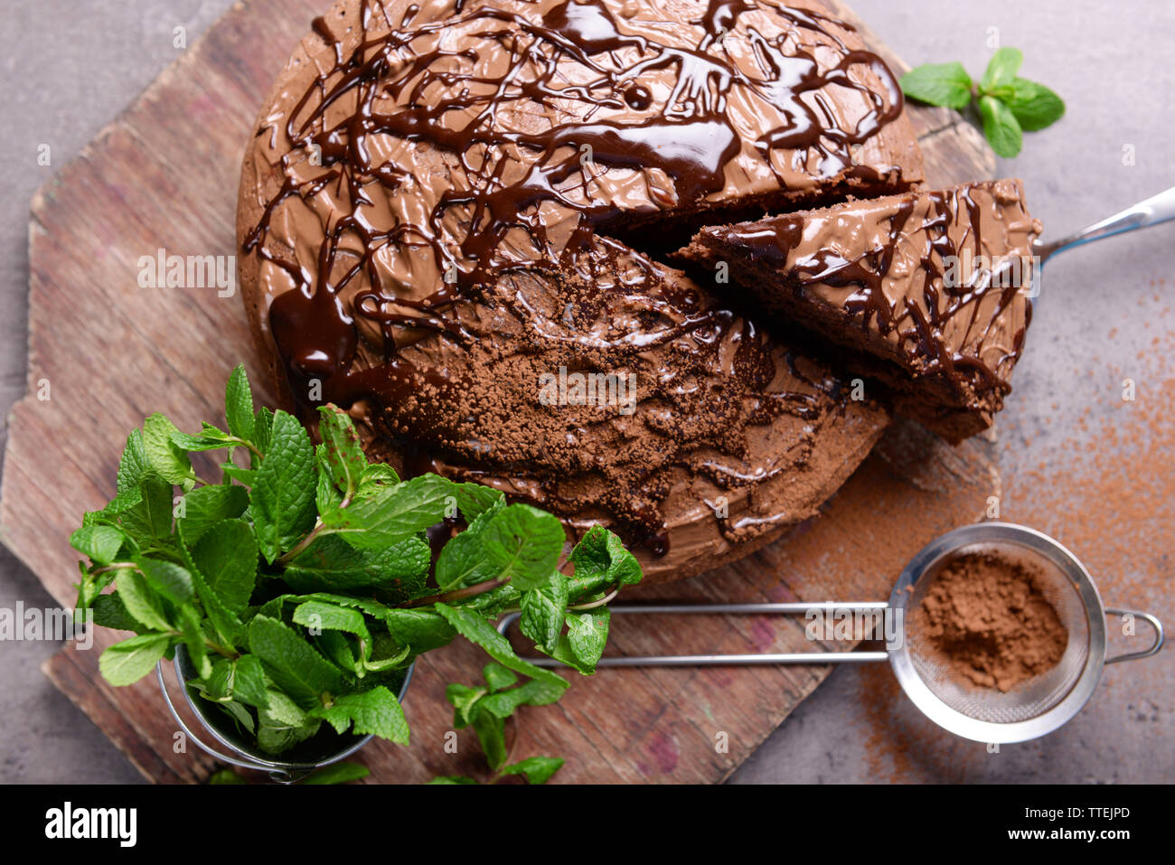 Sliced chocolate pie with pile of mint and sieve on cutting board Stock ...