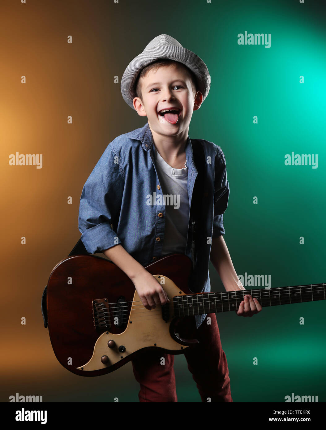 Little boy playing guitar on a dark lighted background Stock Photo - Alamy