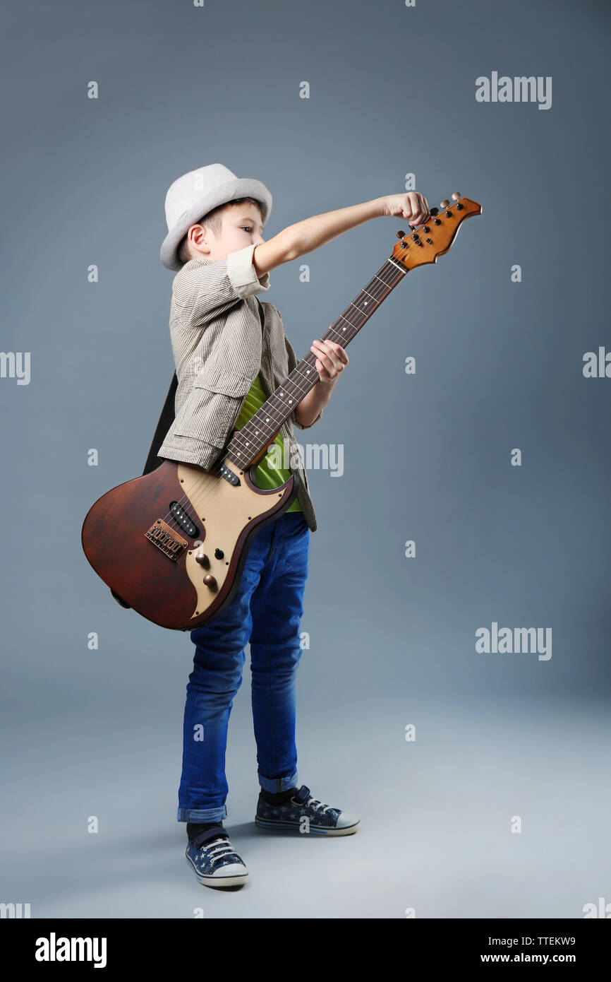 Little boy playing guitar on a grey background Stock Photo - Alamy