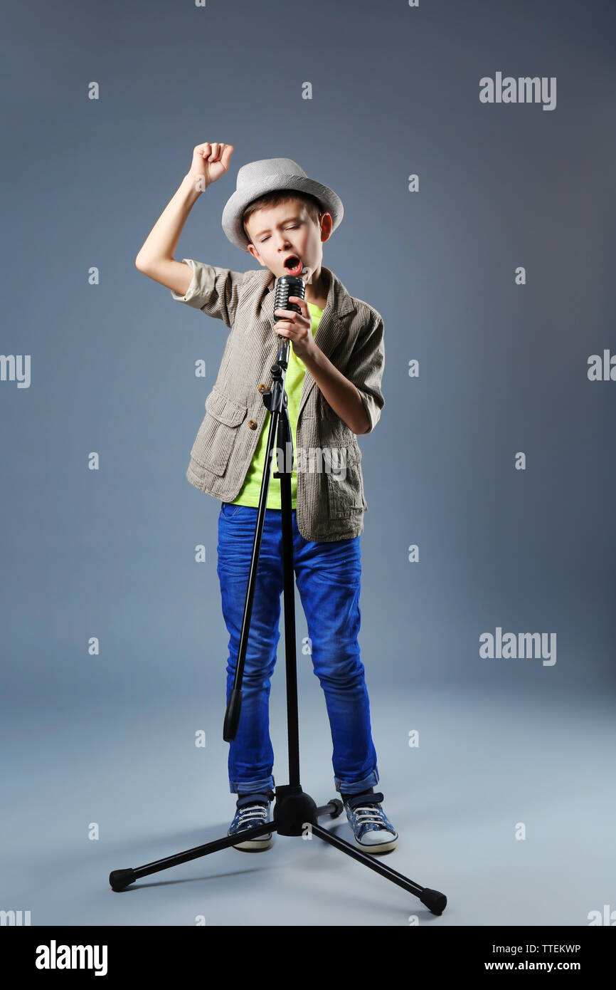 Little boy singing with microphone on a grey background Stock Photo - Alamy
