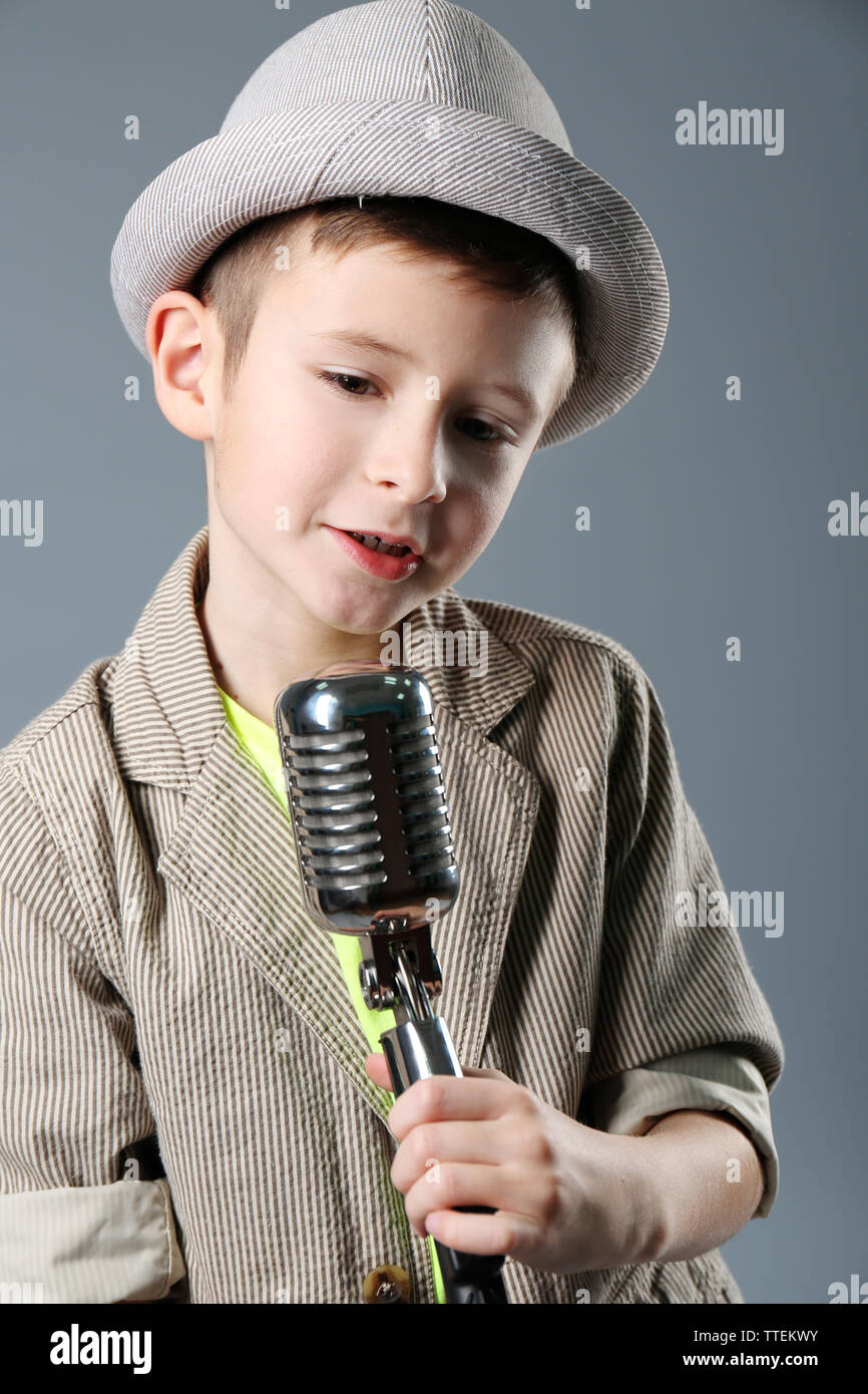 Little boy singing with microphone on a grey background Stock Photo - Alamy