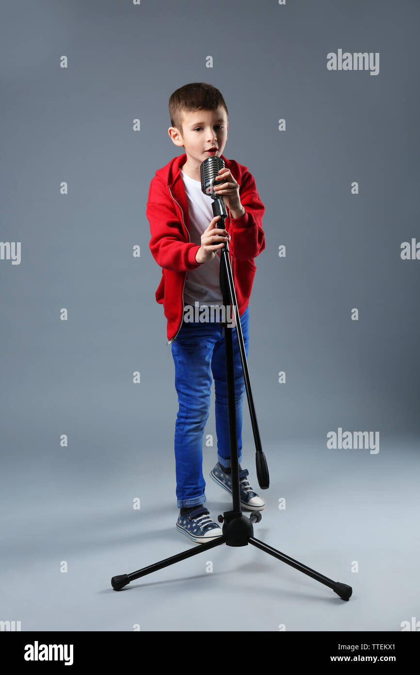 Little boy singing with microphone on a grey background Stock Photo - Alamy