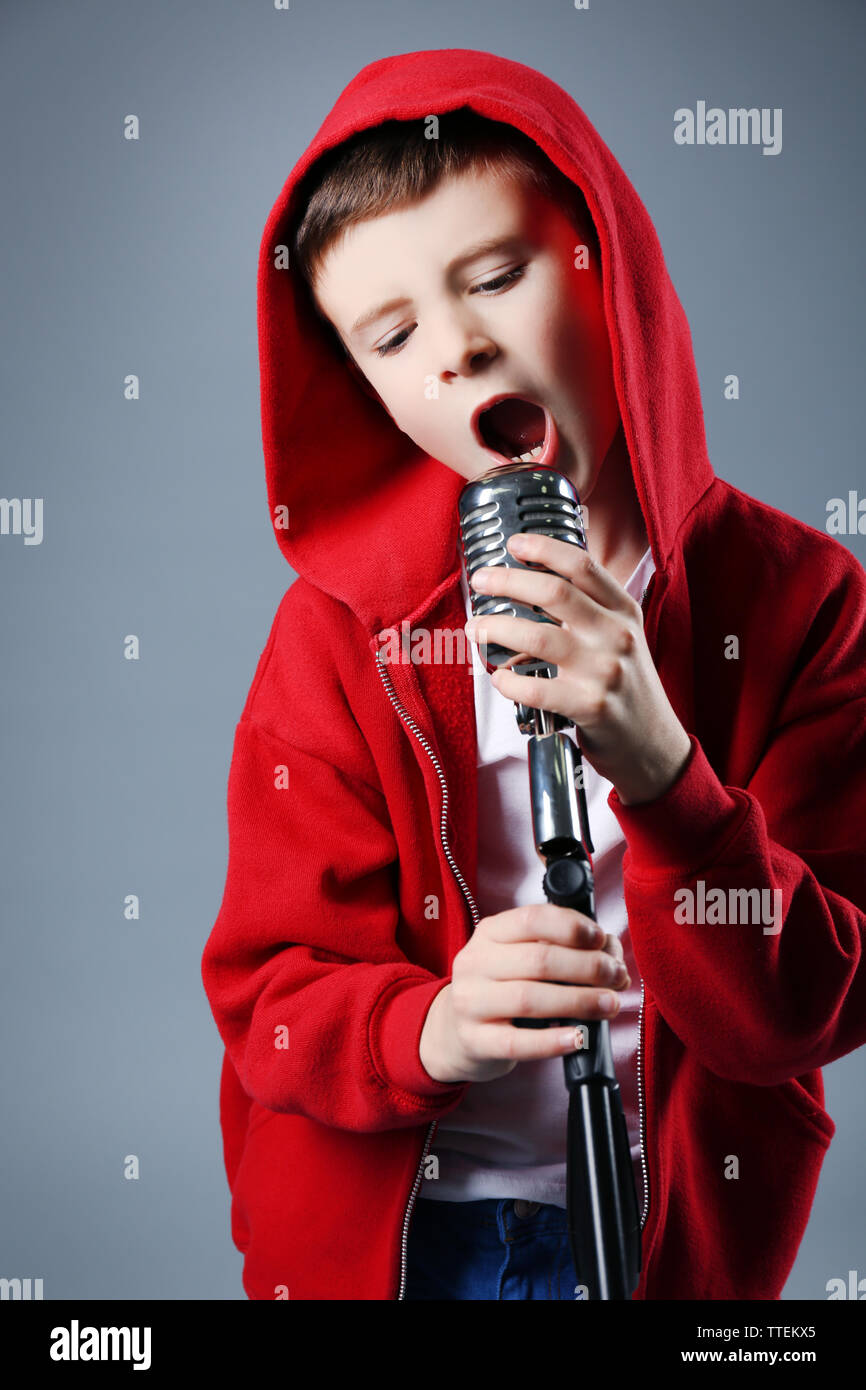 Little boy singing with microphone on a grey background Stock Photo - Alamy