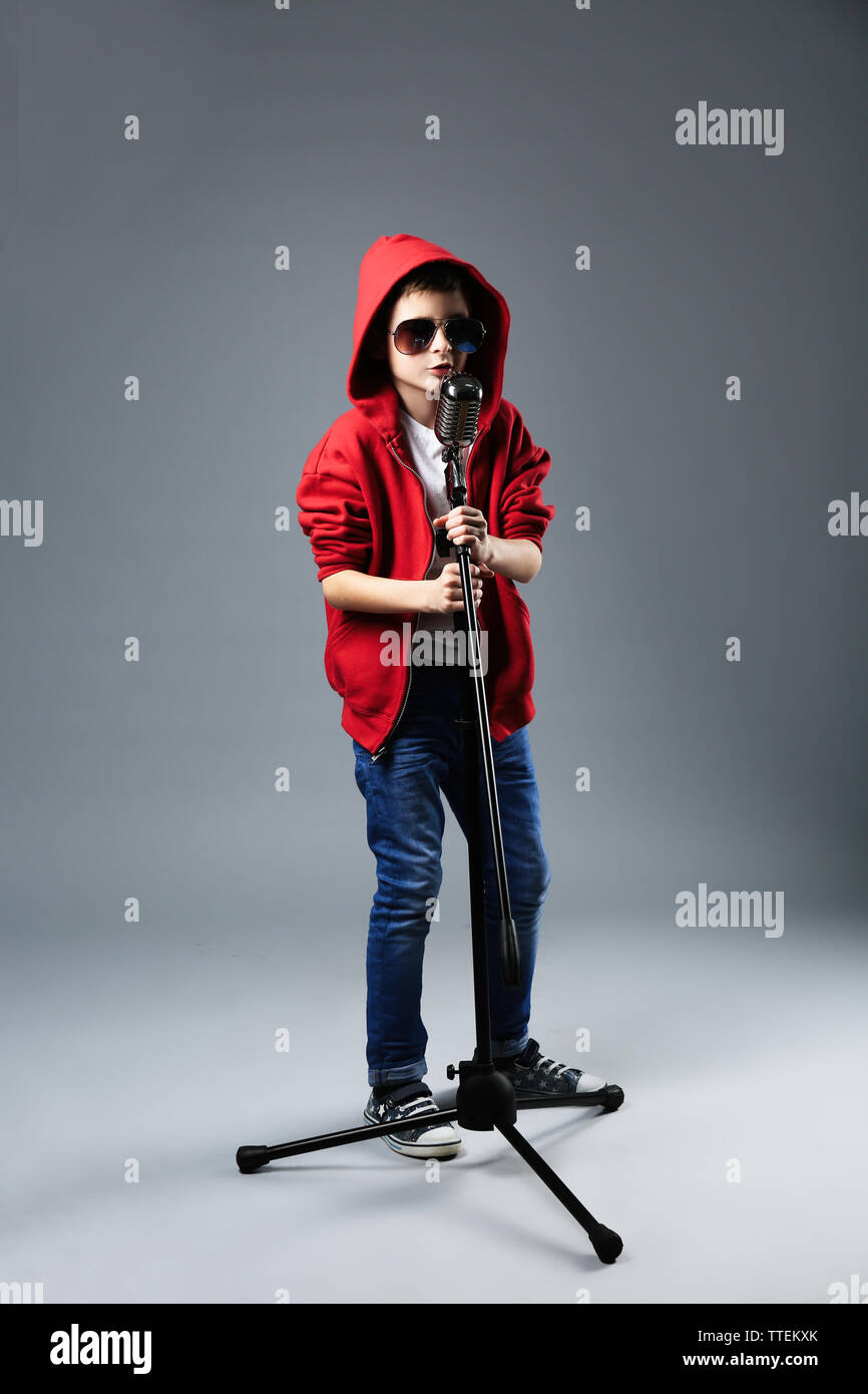 Little boy singing with microphone on a grey background Stock Photo - Alamy