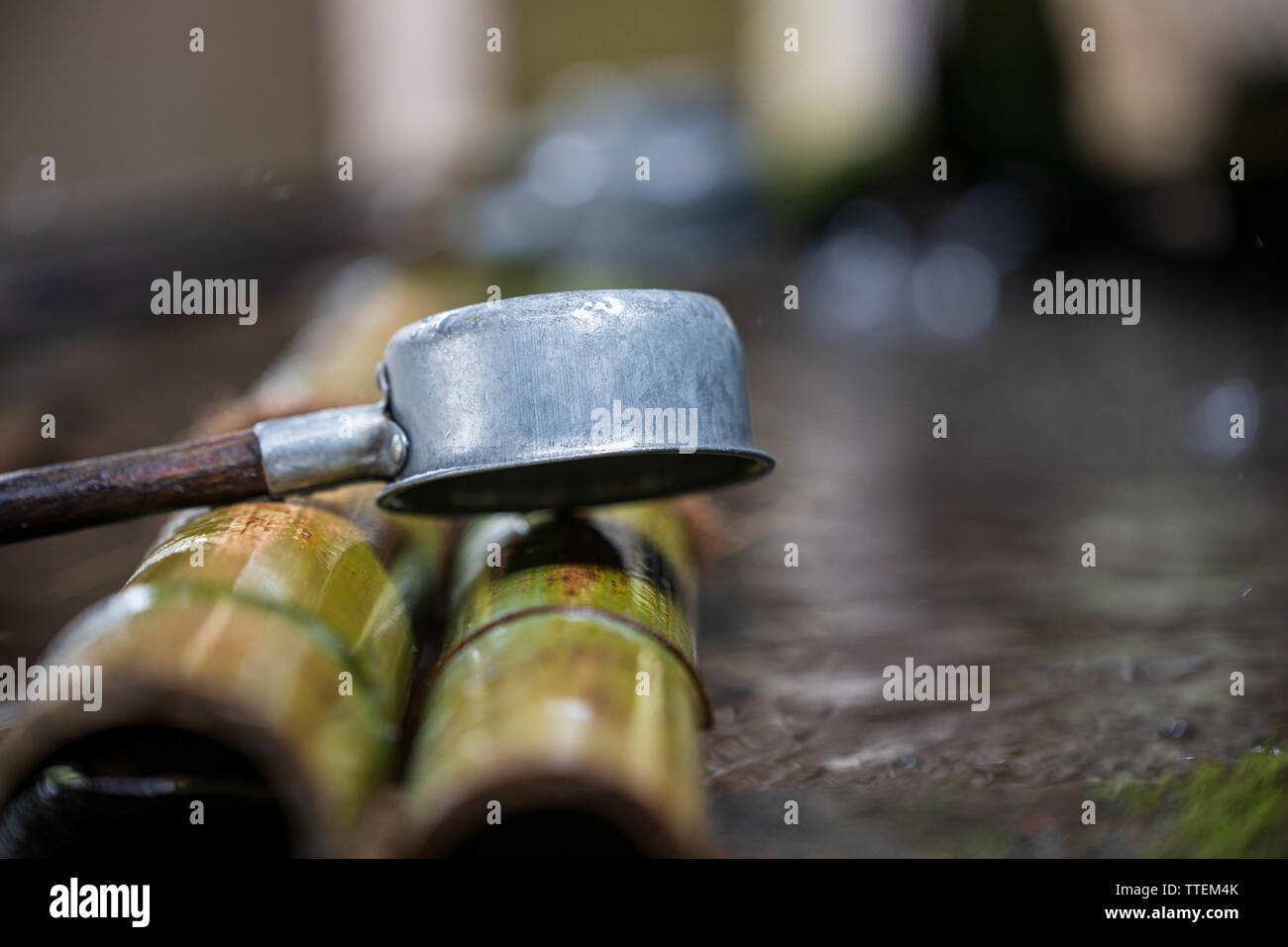 Traditional metal ladle with wooden handle rests on bamboo over stone ...