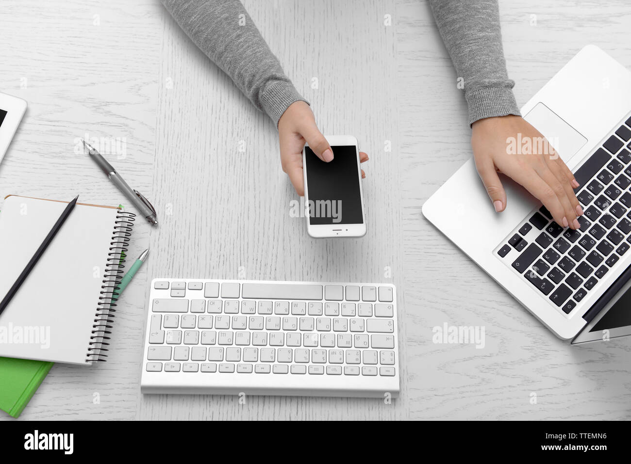 Woman hands at table with computer, tablet, smart phone and other ...