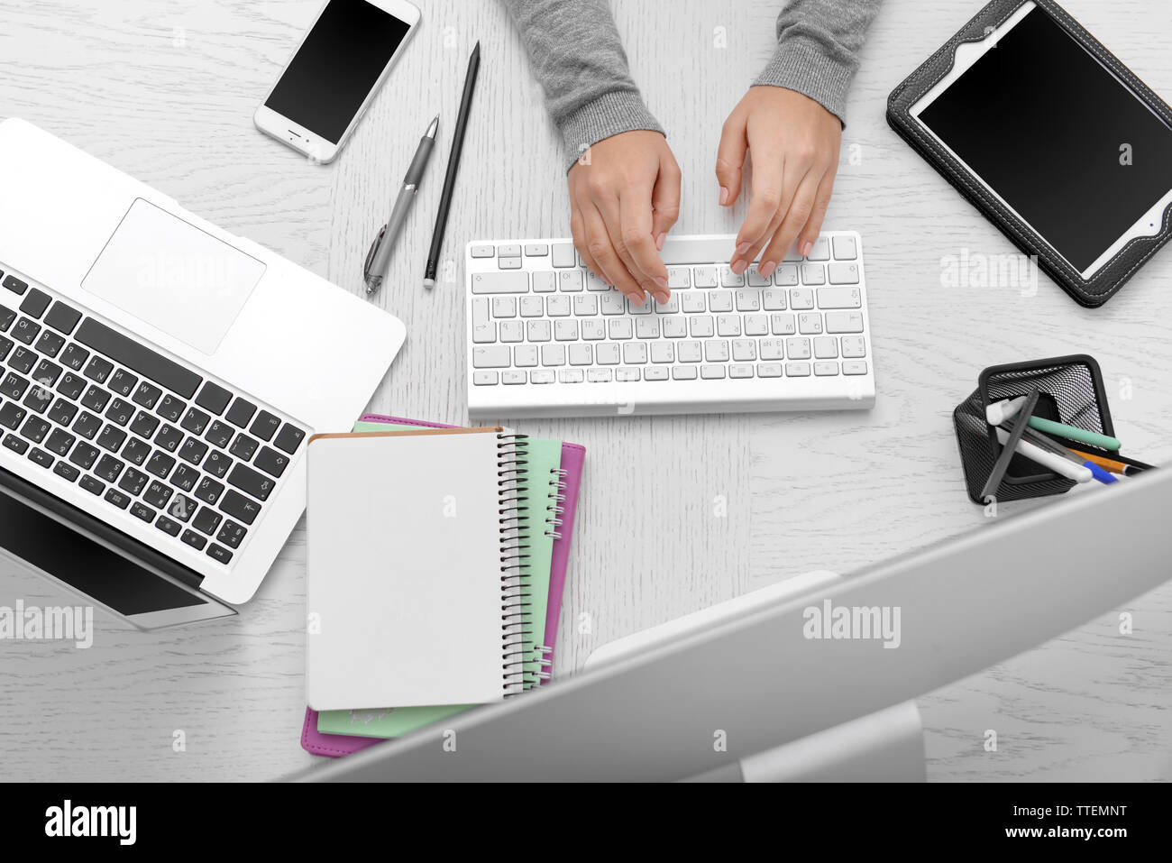 Woman hands at table with computer, tablet, smart phone and other ...
