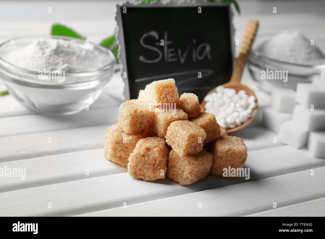Pile of sugar cubes and stevia on white wooden background Stock Photo ...