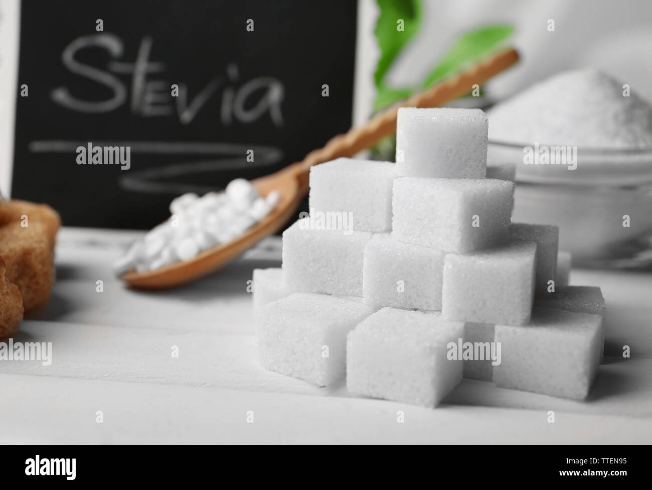 Pile of sugar cubes and stevia on white wooden background Stock Photo ...