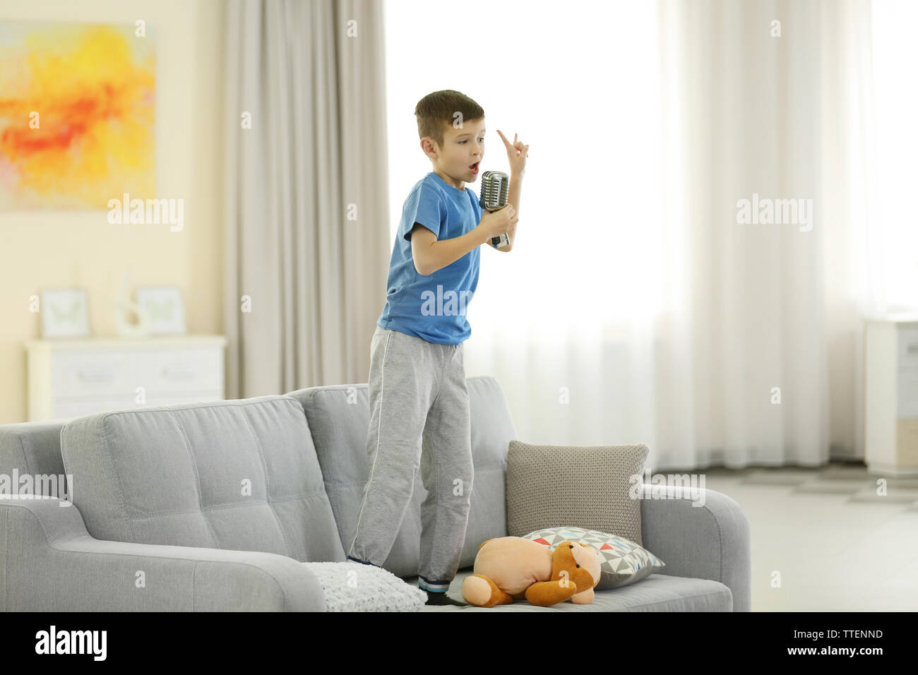Little boy singing with microphone on a sofa at home Stock Photo - Alamy