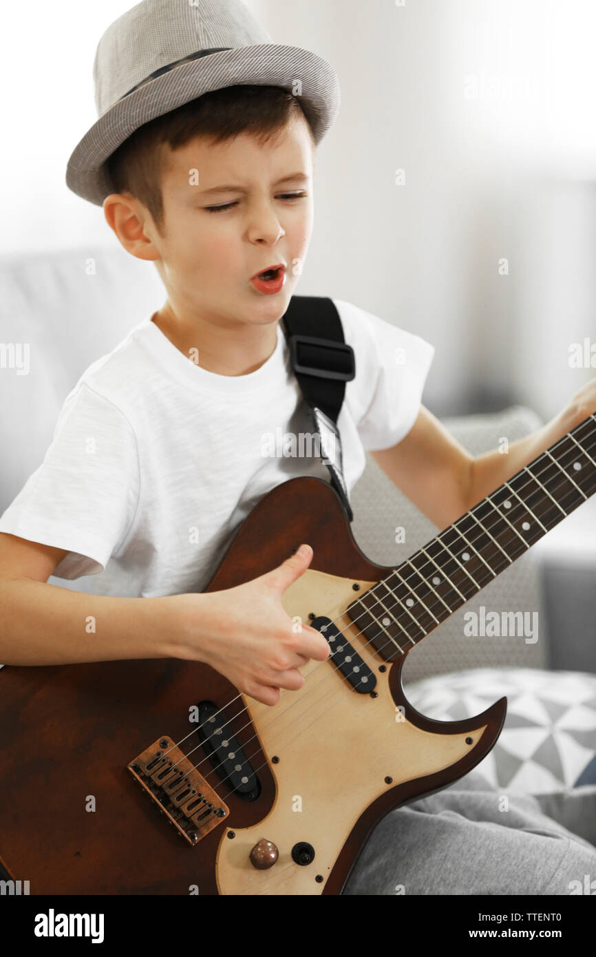 Little boy playing guitar on a sofa at home Stock Photo - Alamy