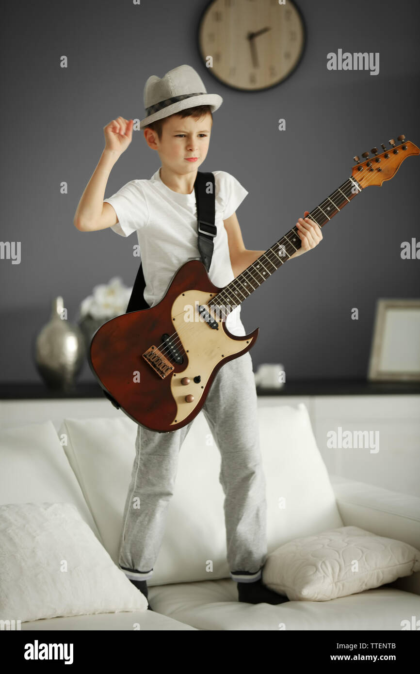 Little boy playing guitar on a sofa at home Stock Photo - Alamy