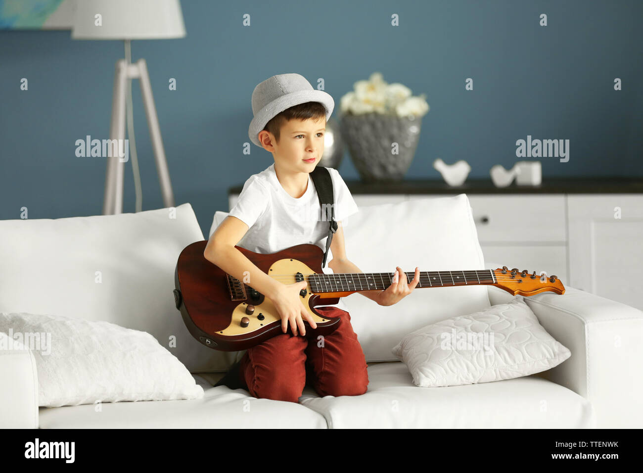Little boy playing guitar on a sofa at home Stock Photo - Alamy
