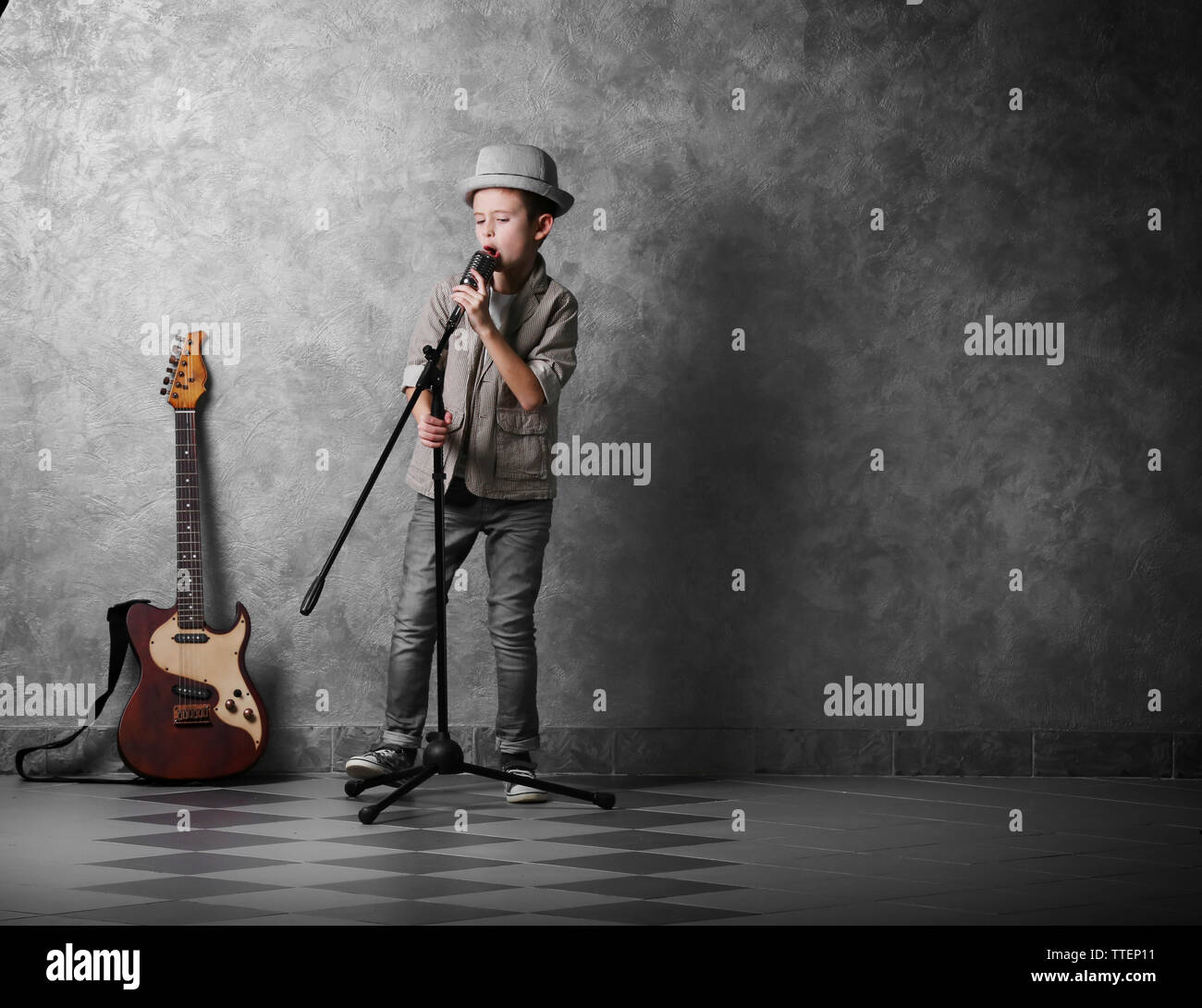 Little boy singing with microphone on a grey wall background Stock ...