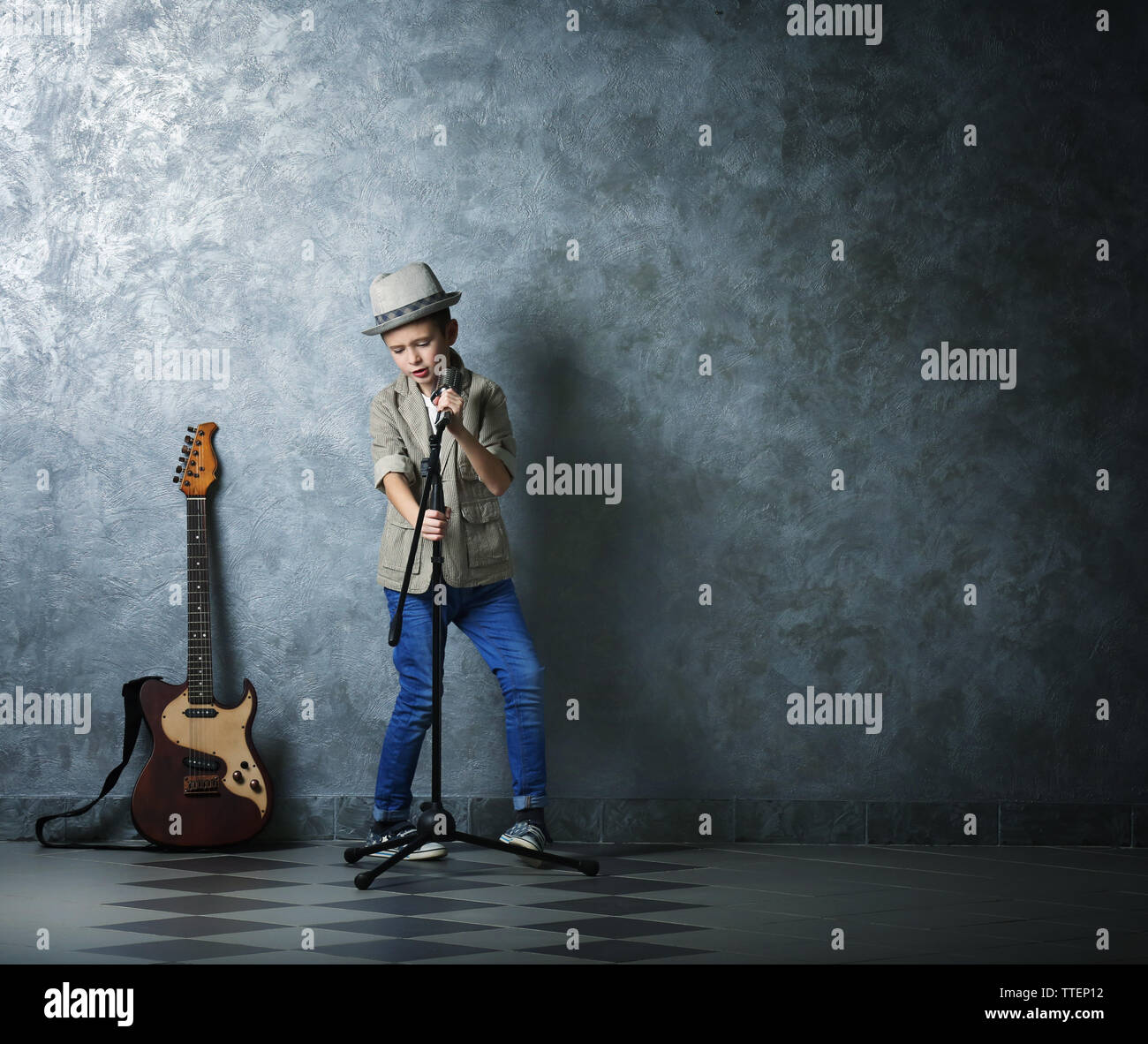 Little boy singing with microphone on a grey wall background Stock ...