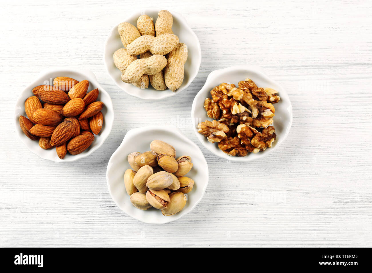 Pistachios, almonds, peanuts and walnut kernels in the bowls on white ...