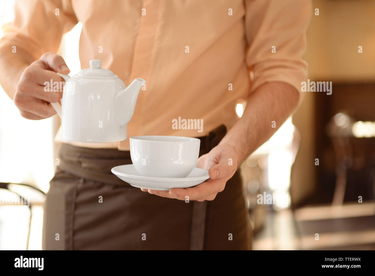 Waiter holding teapot and cup close up Stock Photo - Alamy