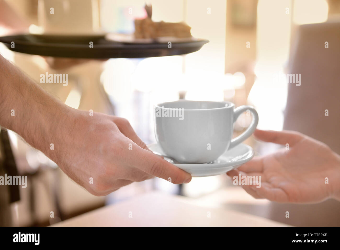 Waiter serving tea to customer in cafe Stock Photo - Alamy