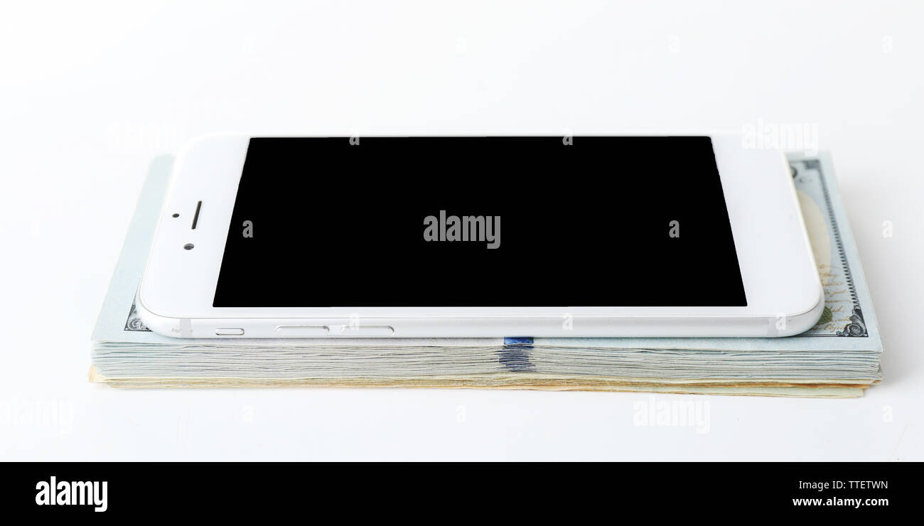Smart phone on a stack of dollar banknotes, isolated on white. Internet ...