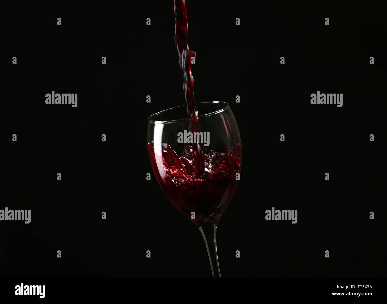 Wine pouring in glass on black background Stock Photo - Alamy