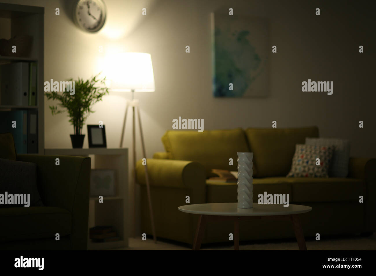 Living room interior with lighted lamp, table and green sofa Stock ...