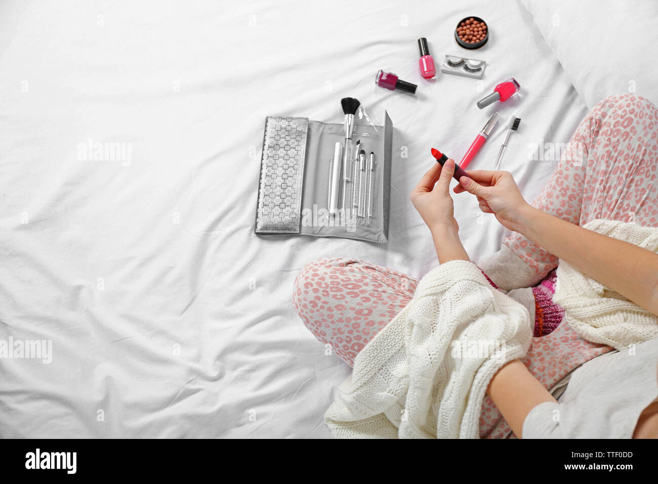 Woman in pajamas applying makeup on her bed Stock Photo - Alamy