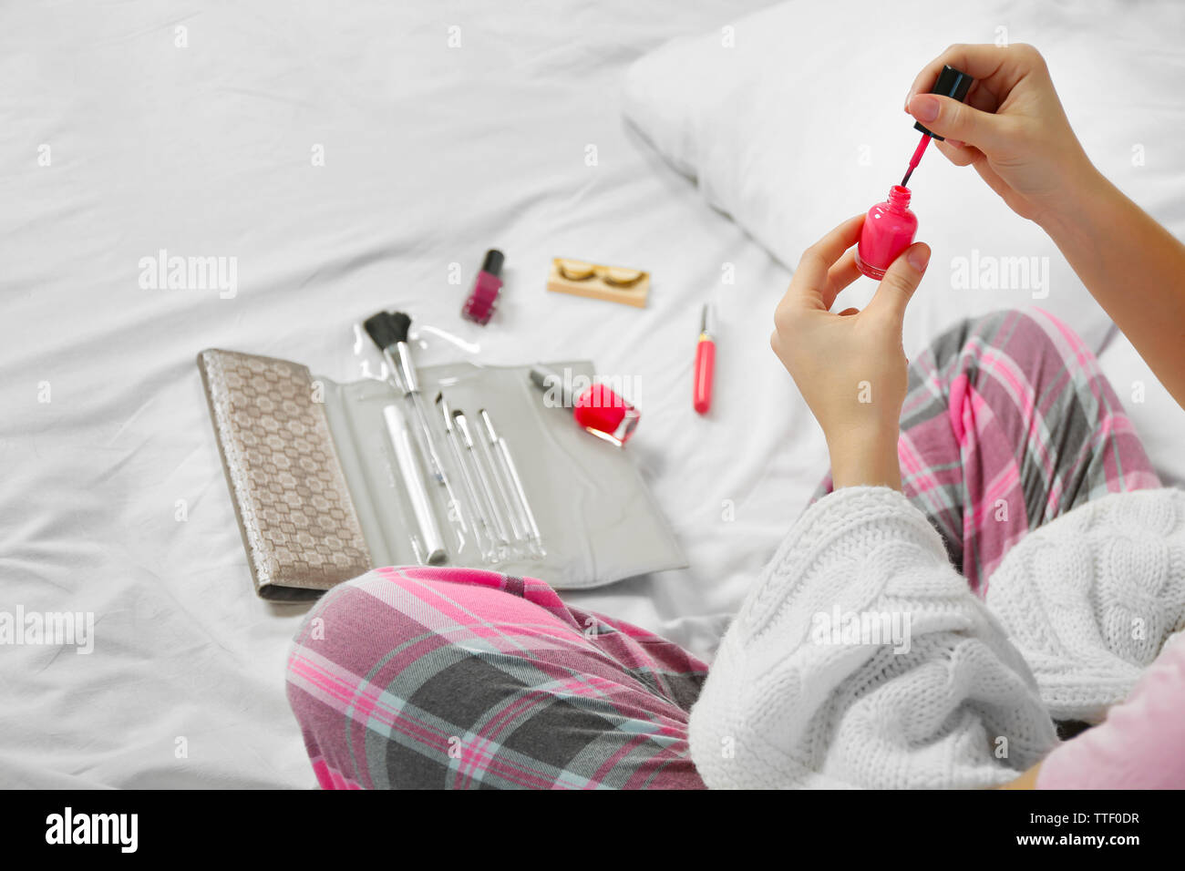 Woman in pajamas applying makeup on her bed Stock Photo - Alamy