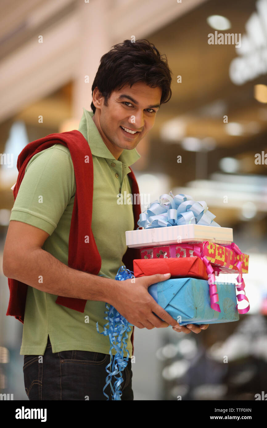 Man holding gifts in a shopping mall Stock Photo - Alamy