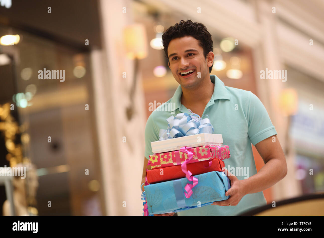 Man holding gifts in a shopping mall Stock Photo - Alamy