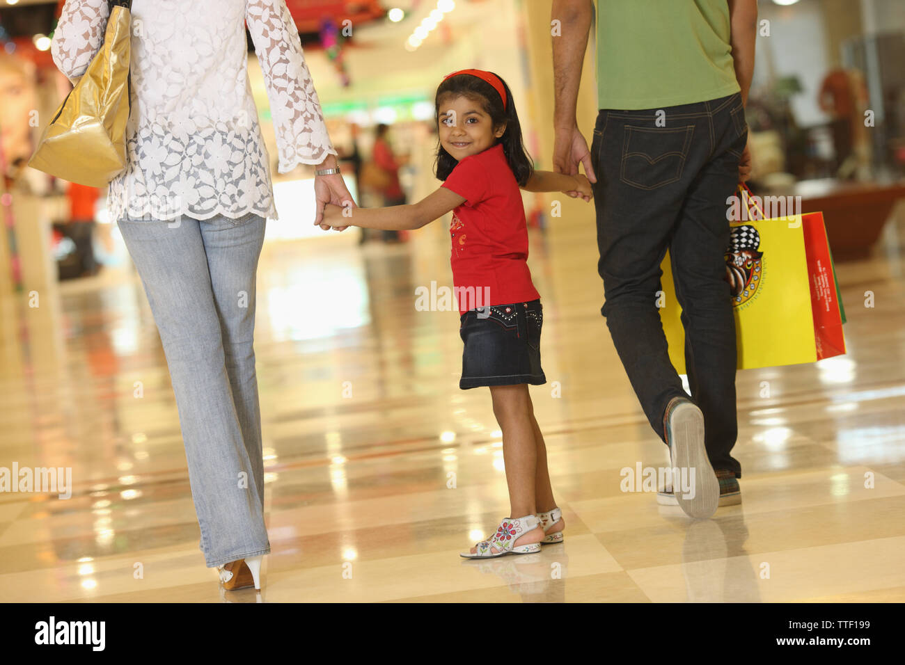 Girl with her parents walking though a shopping mall Stock Photo - Alamy