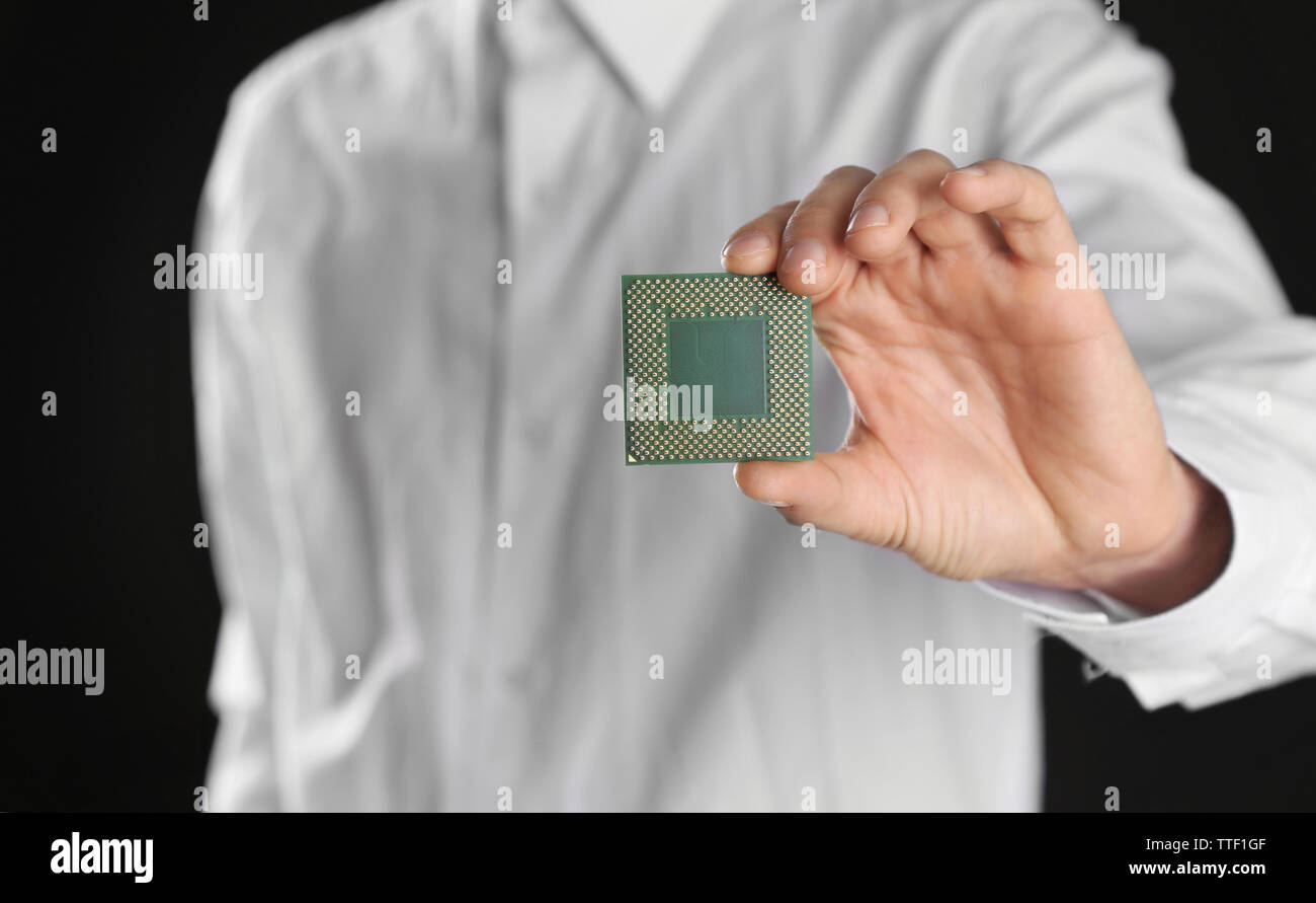 Man holding microprocessor in his hand on black background Stock Photo ...