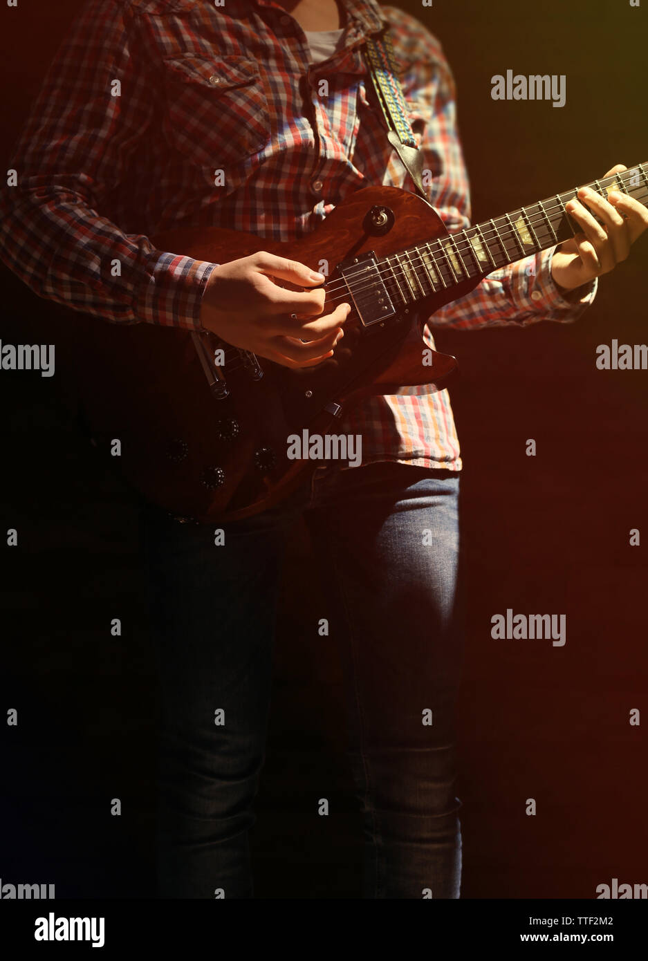 Young man playing electric guitar on dark lighted background Stock ...