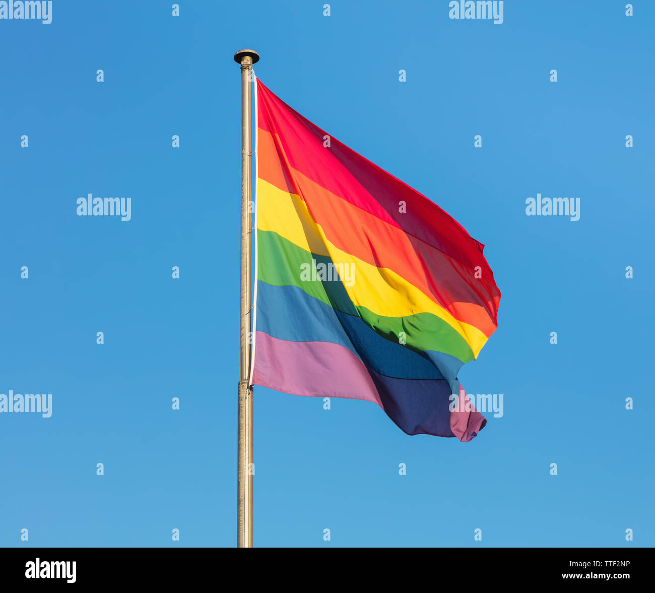 Rainbow flag of the LGBT movement against clear blue sky at sunset ...