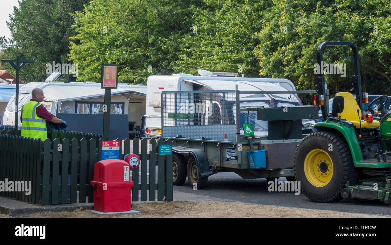 Male site operative on refuse collection duties, next to tractor and ...