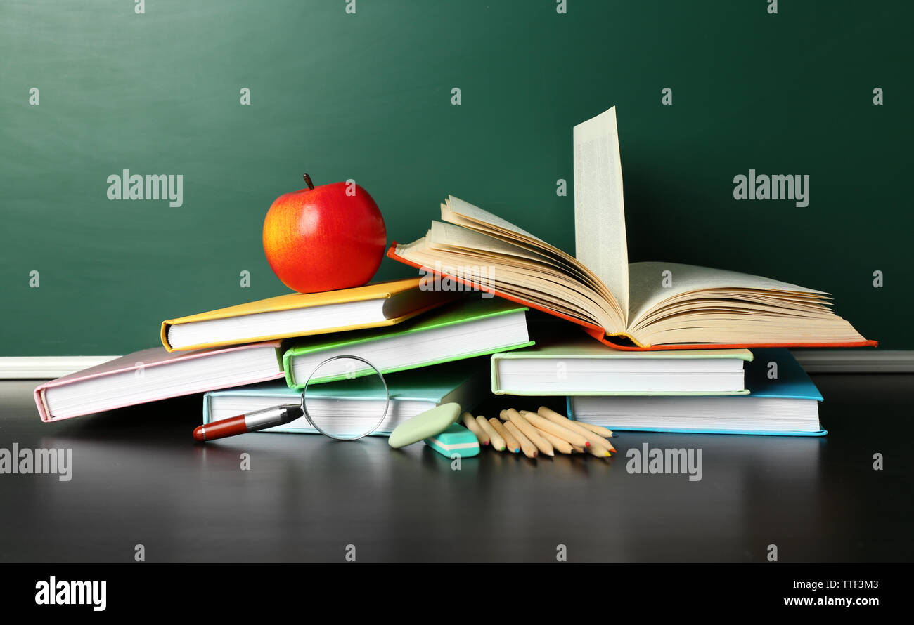 School books on desk near chalkboard Stock Photo - Alamy