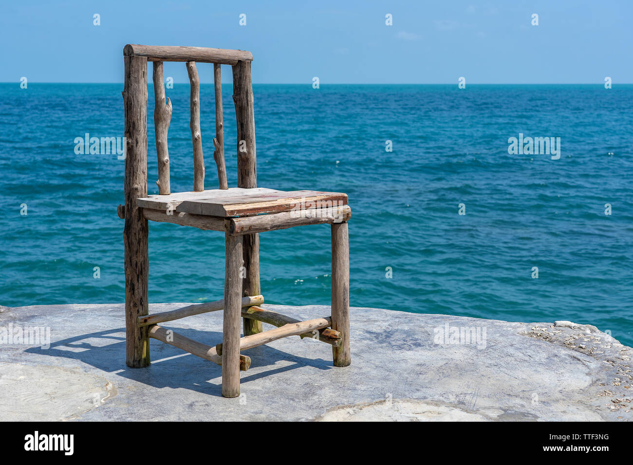 Wooden chair in empty cafe next to sea water in tropical beach. Close up. Island Koh Phangan ...