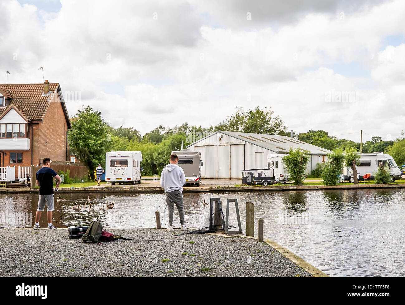 Two teenage males lure fishing for pike and perch on the River Bure in ...