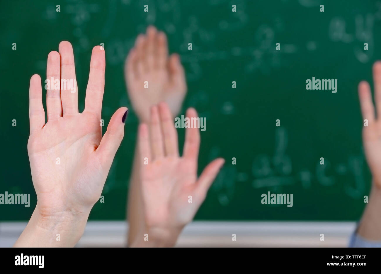 Raised hands on blackboard background in class Stock Photo - Alamy