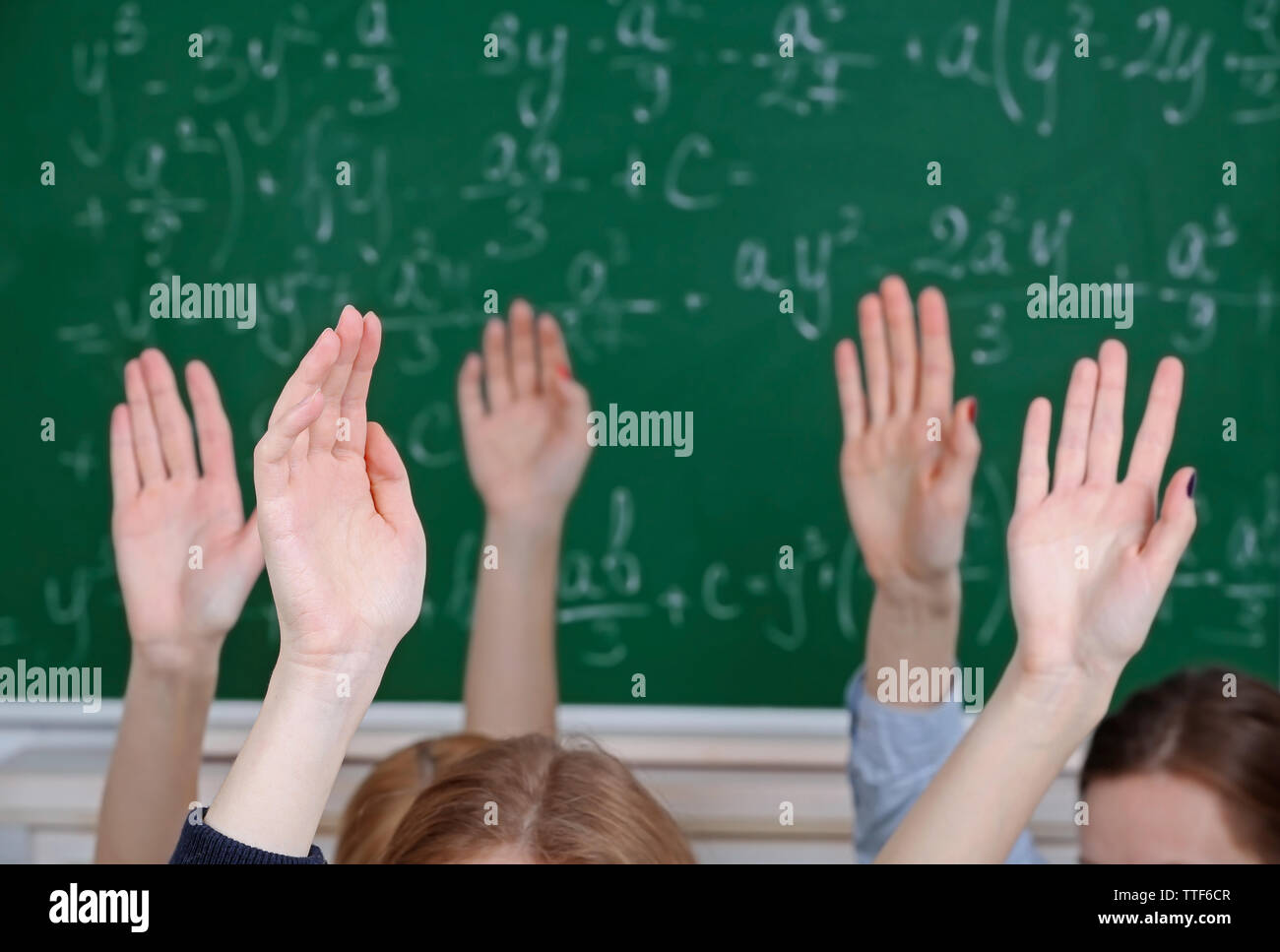 Raised hands on blackboard background in class Stock Photo - Alamy
