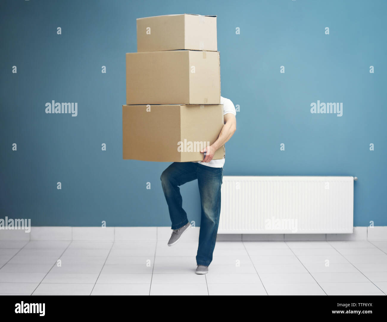 Man holding pile of carton boxes against blue wall in the room Stock ...