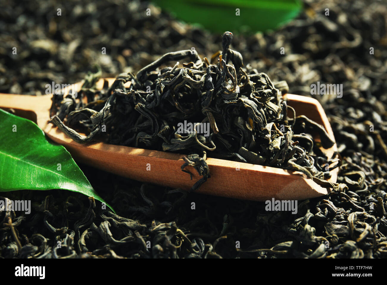 Pile of dry tea with wooden spoon and green leaves, close up Stock ...